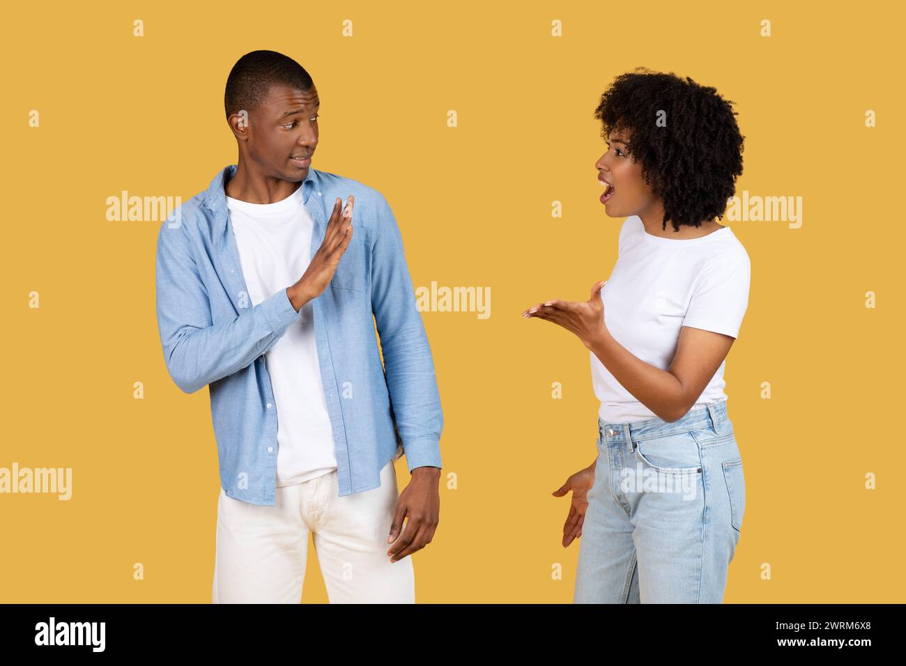 A man defensively gesturing stop with his hand as a woman animatedly ...