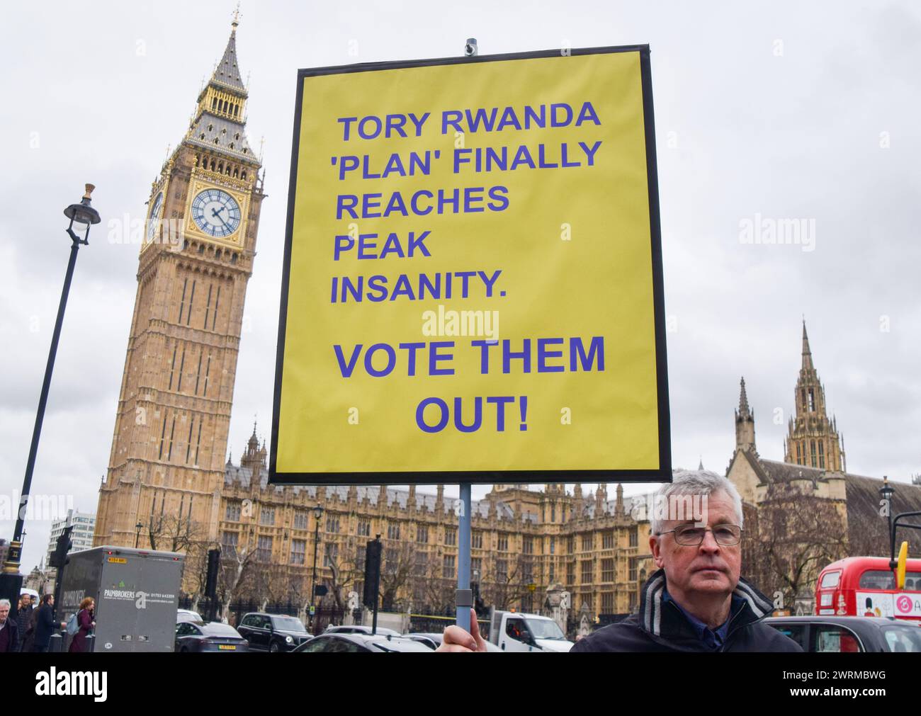 London, UK. 13th March 2024. A protester holds a placard criticizing ...