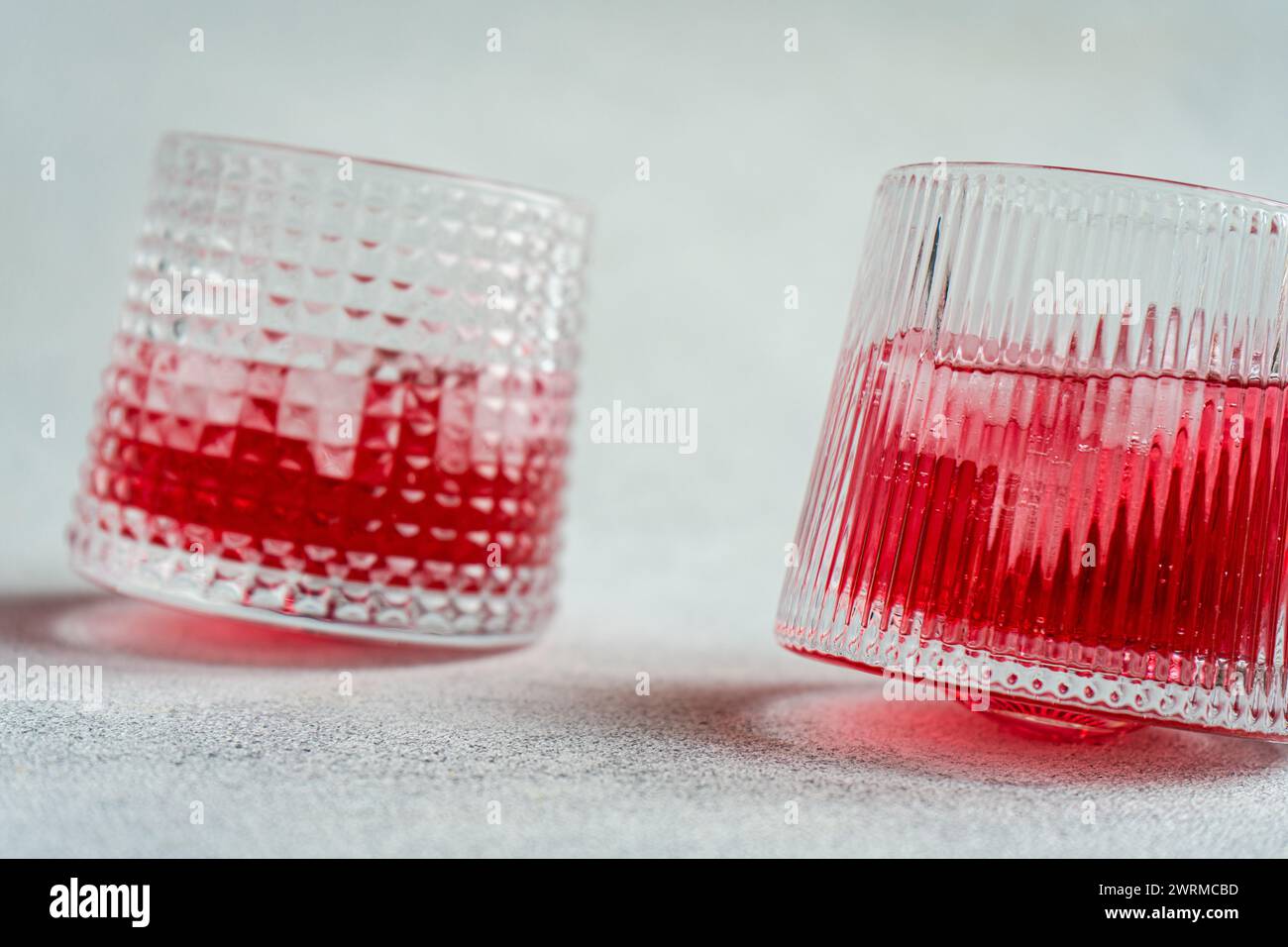 Two textured glasses filled with ice and a vibrant cherry vodka and ...