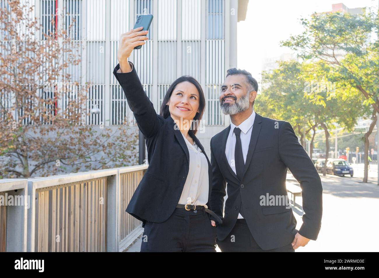 Two professional business colleagues are posing for a selfie with a ...