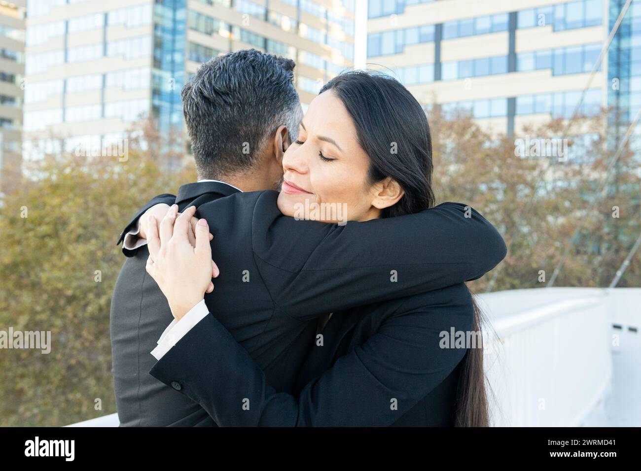 Two business colleagues in formal attire sharing a supportive embrace ...