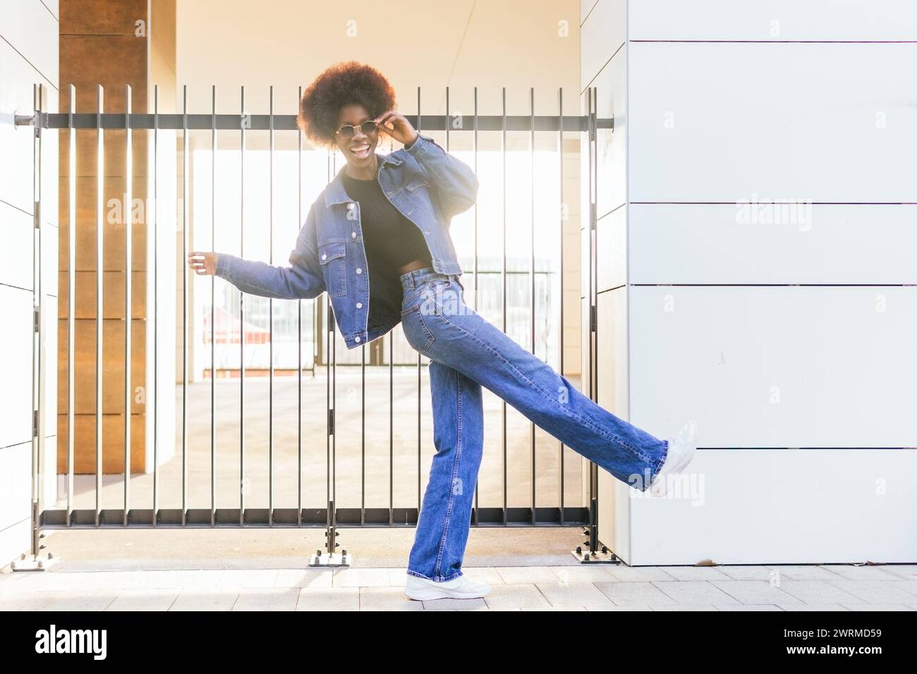 A woman caught in mid-twirl enjoys a playful moment in her denim outfit ...