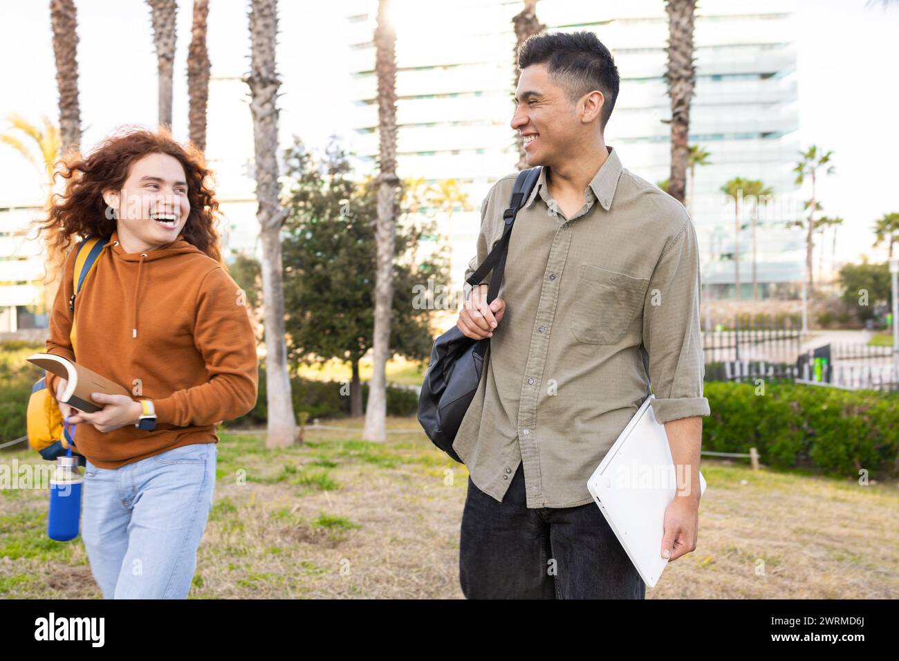 Diverse students laugh and converse outside with a laptop and reusable ...
