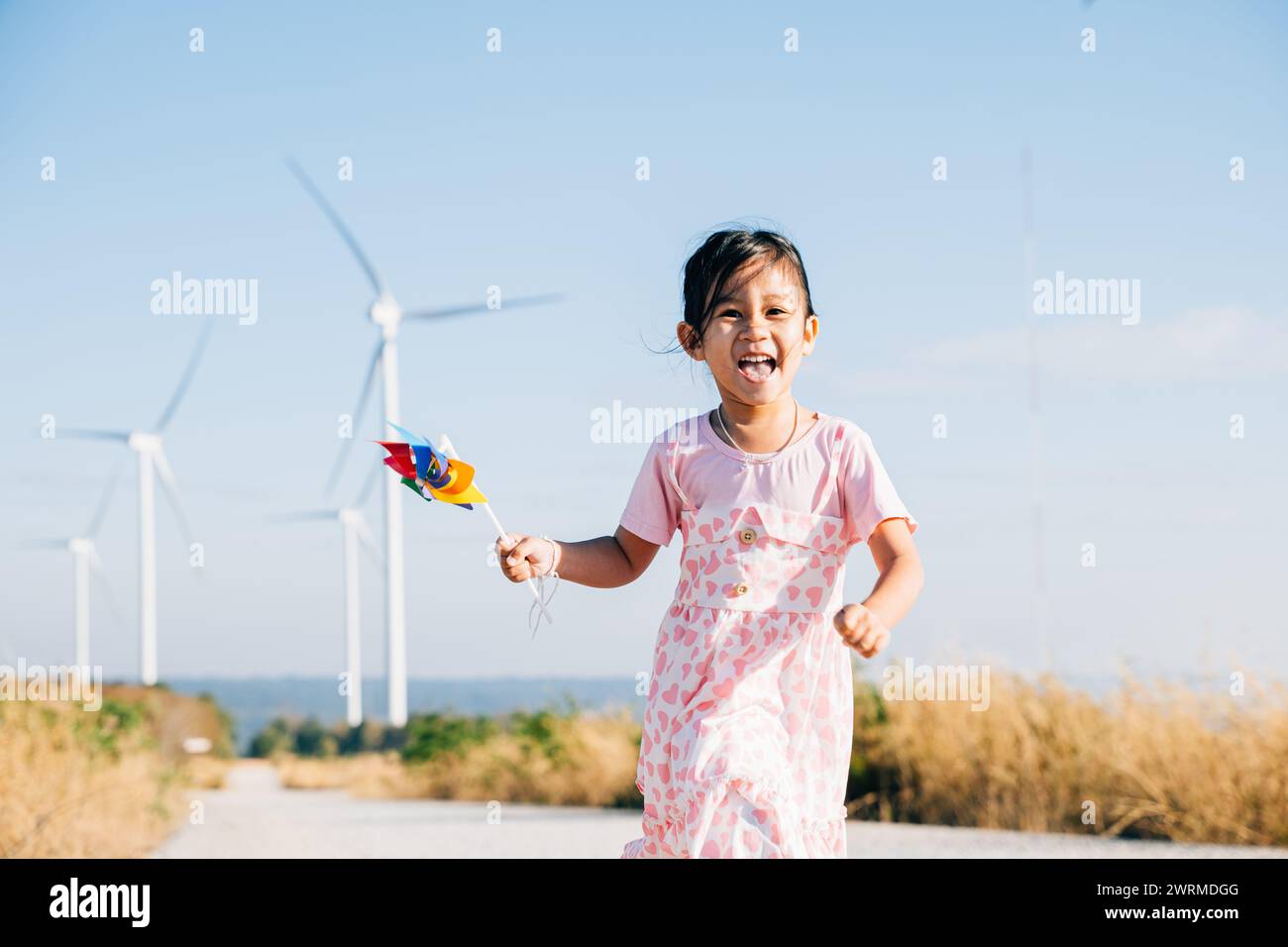 Child's playful exploration by windmills, little girl runs with ...