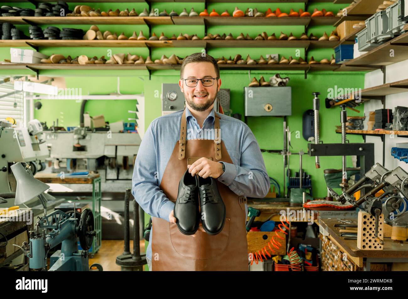 A cheerful shoemaker stands in a well-equipped workshop in Austria ...