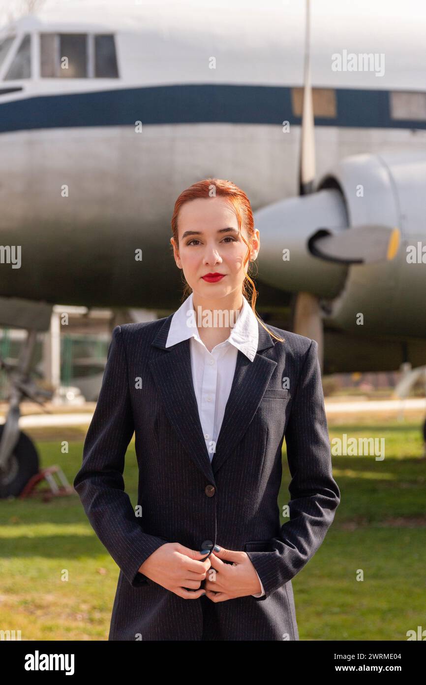 A confident air hostess in a formal uniform stands before a classic ...
