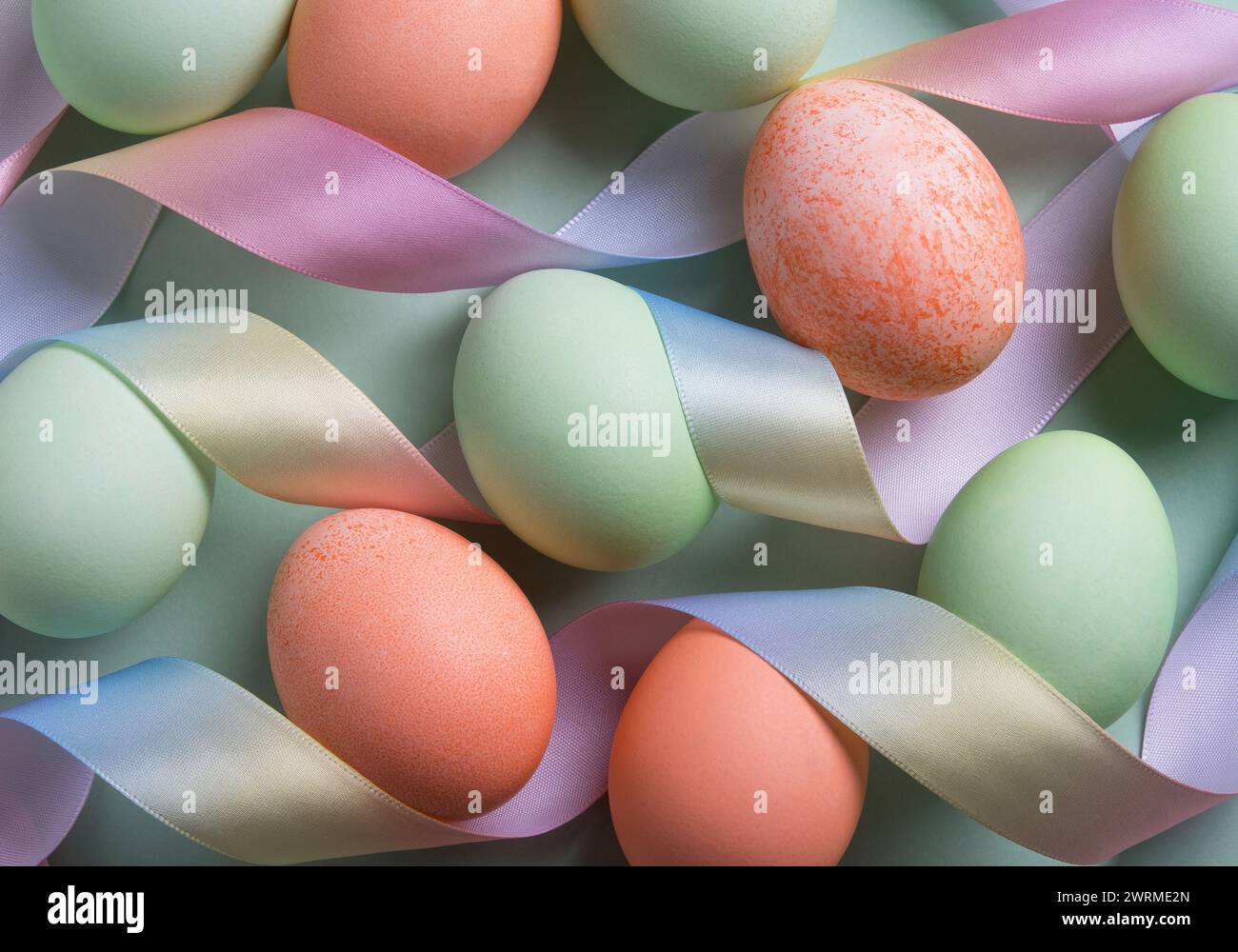 Top view pastel-colored Easter eggs nestled between silky ribbons, an ...