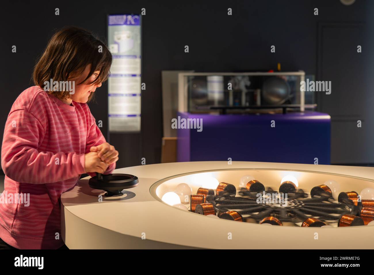 A curious girl engaging with a hands-on display at a science museum ...