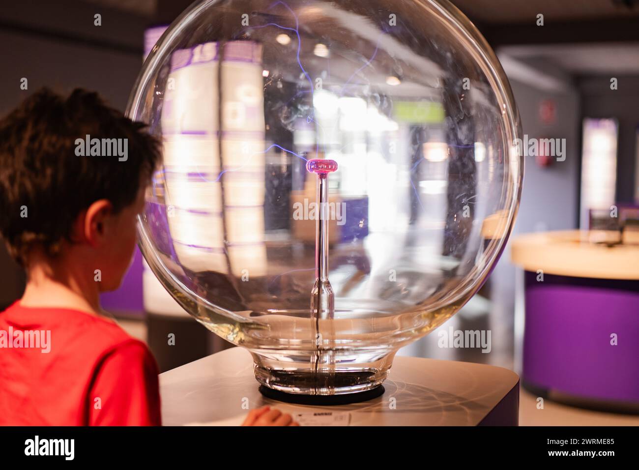 A young boy fascinated by a large plasma globe at a science museum ...