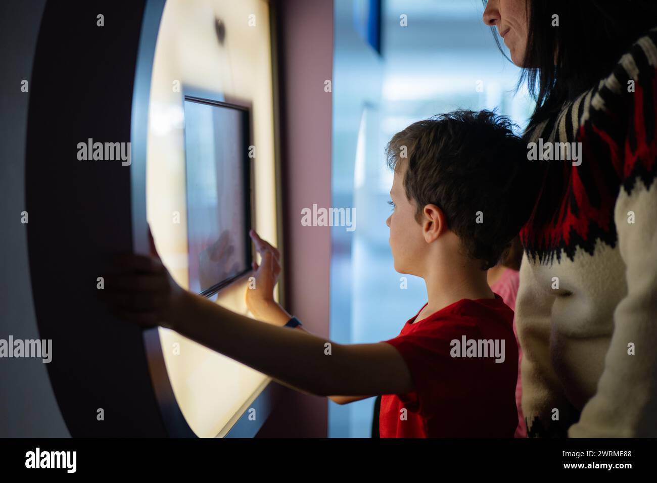 A boy and a woman engage with a touch screen at a science museum ...