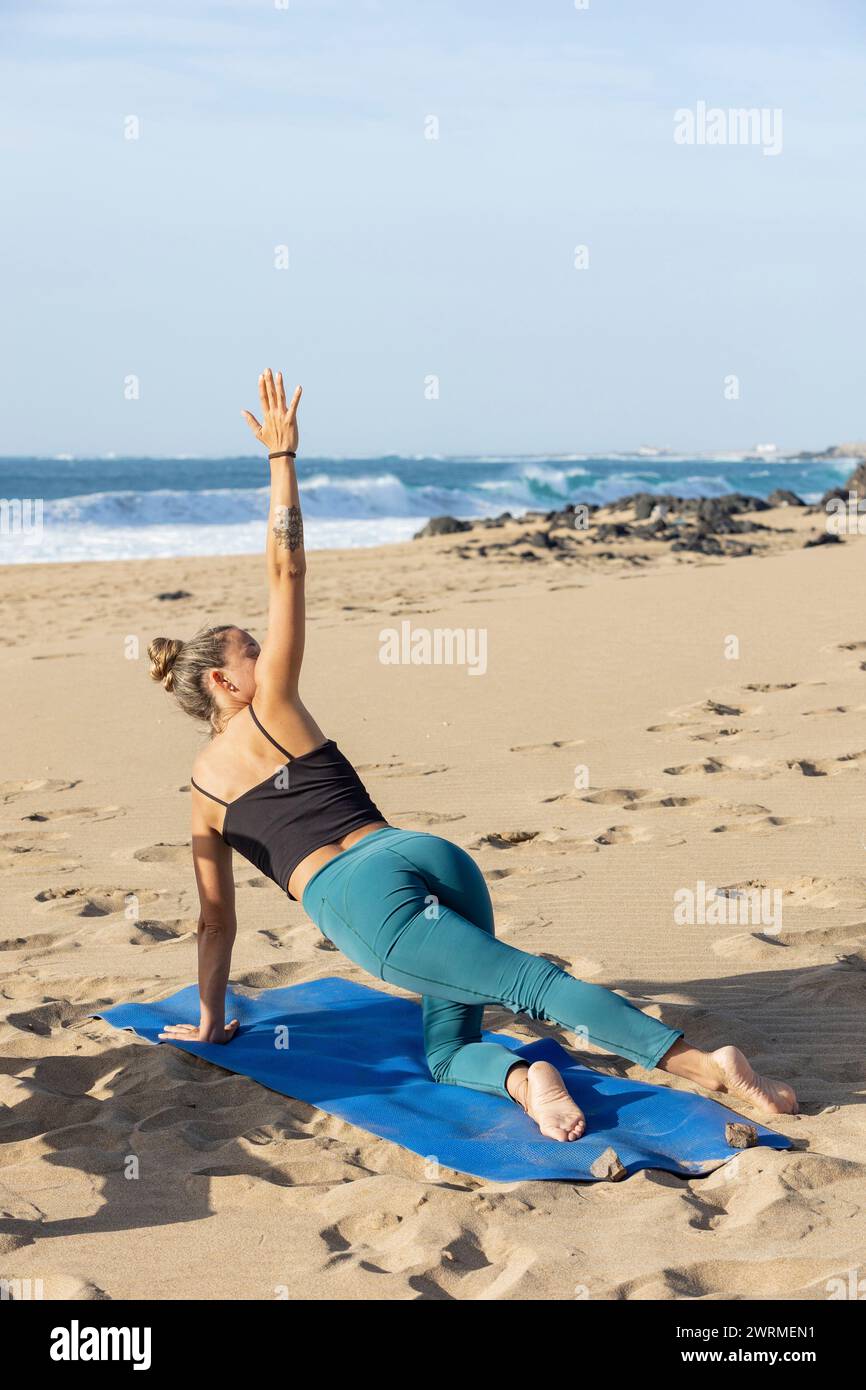 A woman practices a Side Plank (Vasisthasana) during a tranquil yoga ...