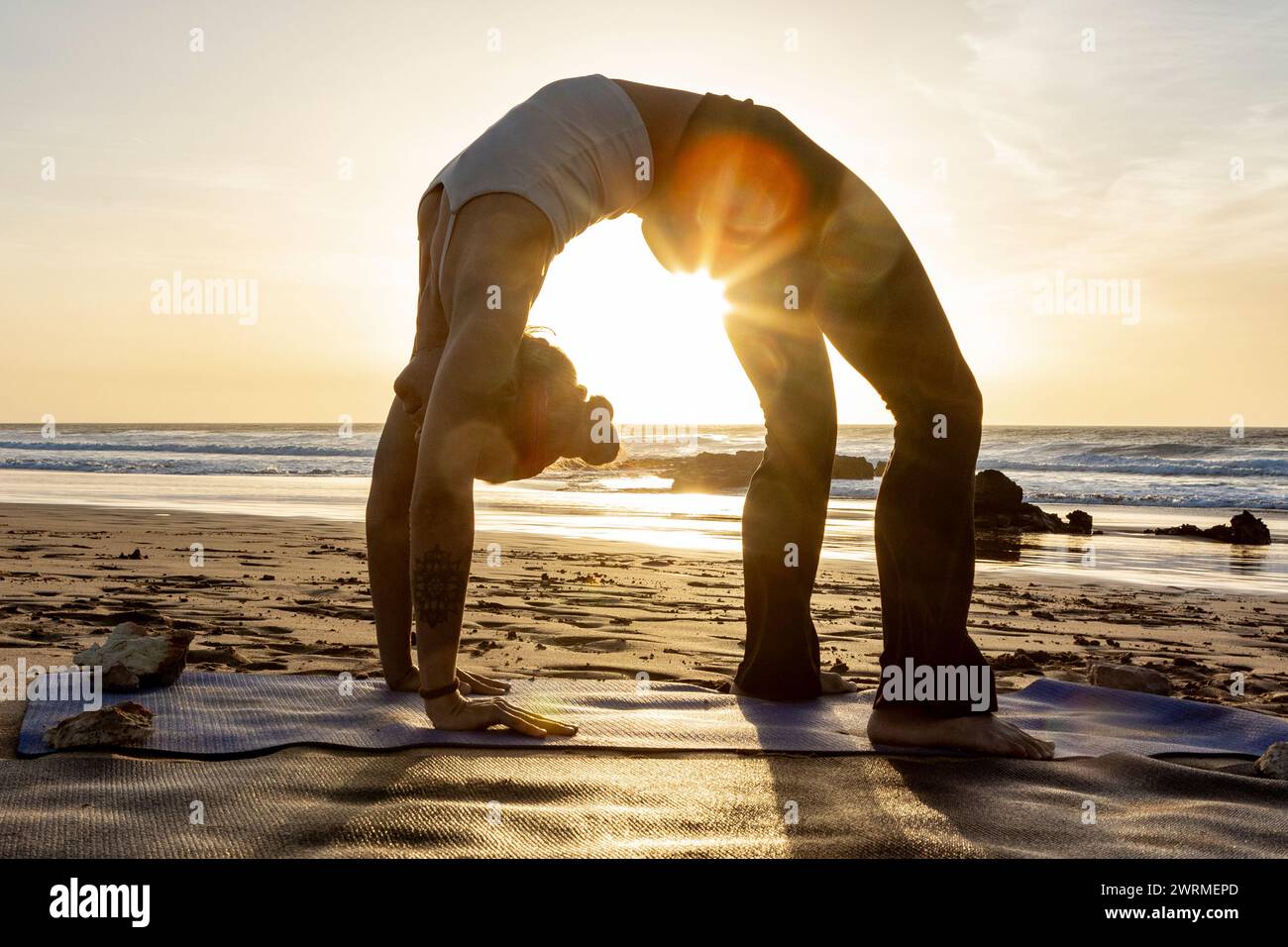 Practicing an advanced yoga backbend, the Wheel Pose, during a serene ...