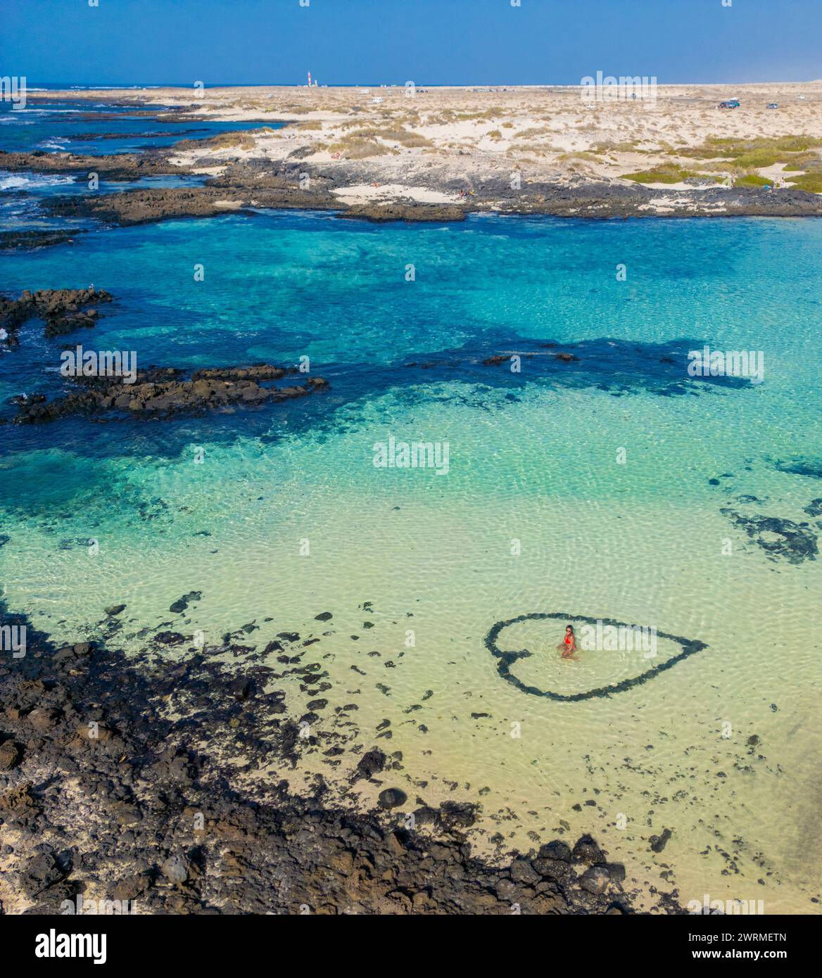 An aerial view captures a woman standing within a heart-shaped natural ...