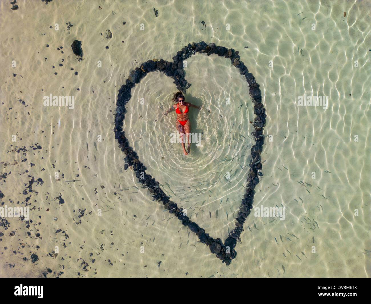 An aerial image captures a woman lying within a heart shape formed by ...