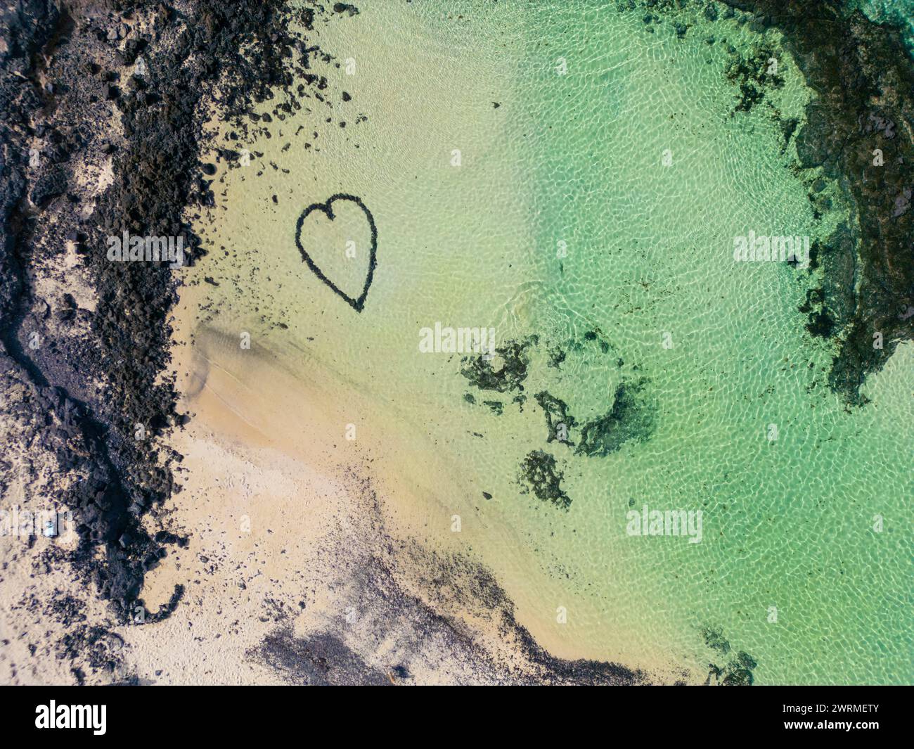 Aerial view of a natural heart-shaped mark on the beach with crystal ...