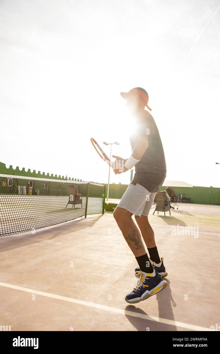 An unrecognizable male tennis player with a back view, about to hit a ...
