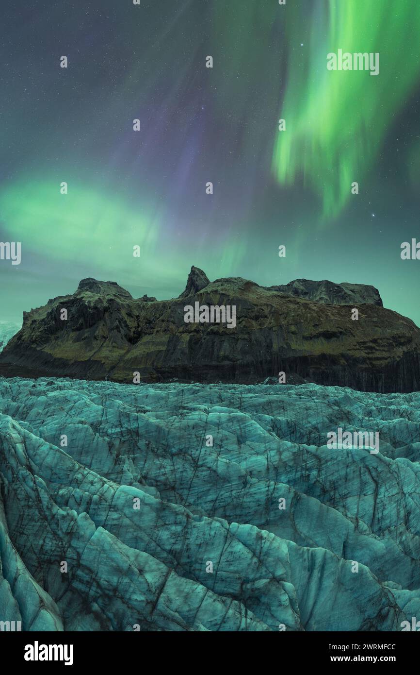 Northern lights dance above the rugged terrain of Iceland, illuminating ...