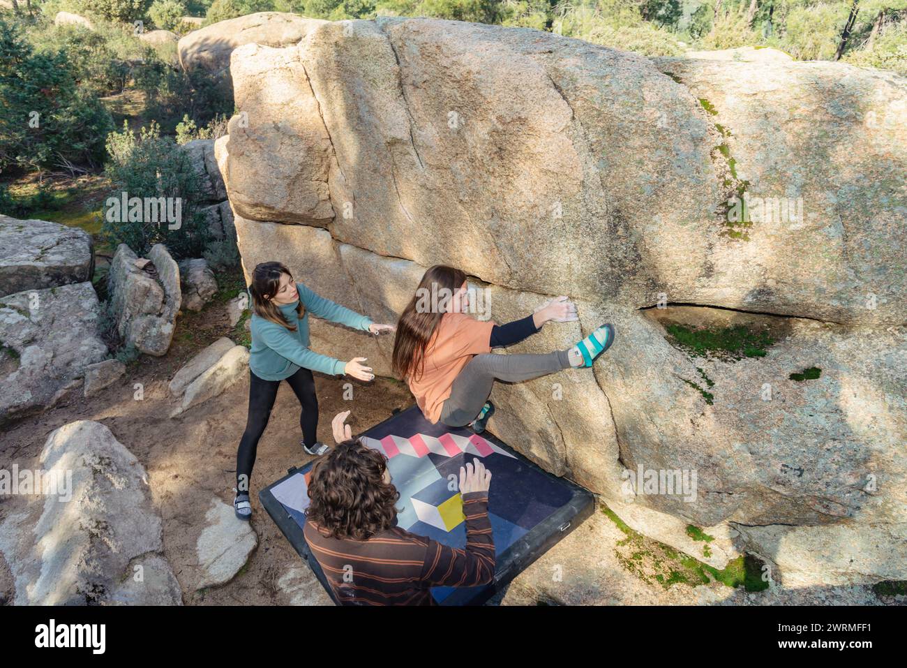 From above of focused climbers work in unison on a boulder problem ...