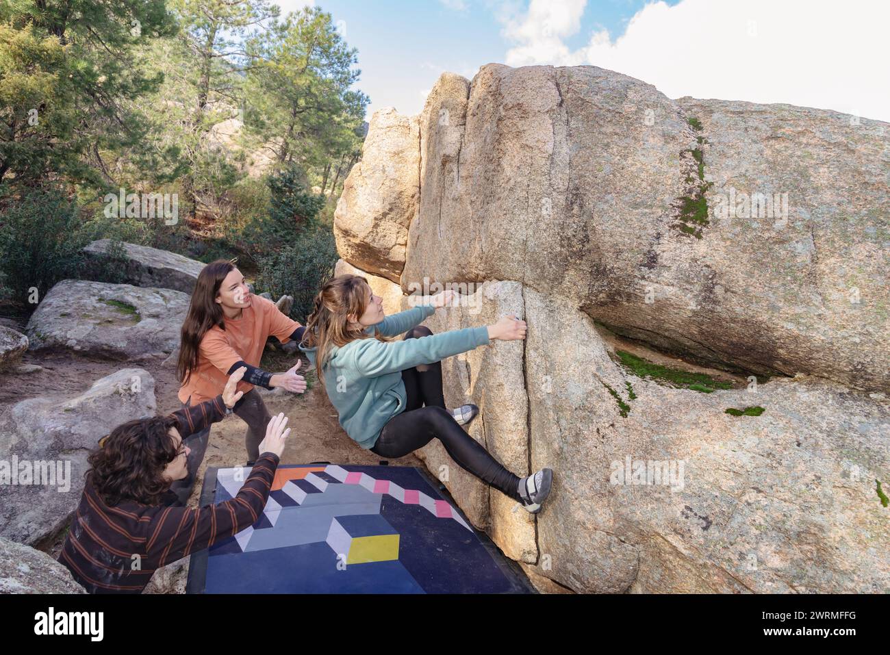 A climber is assisted by friends while navigating a tricky section of a ...