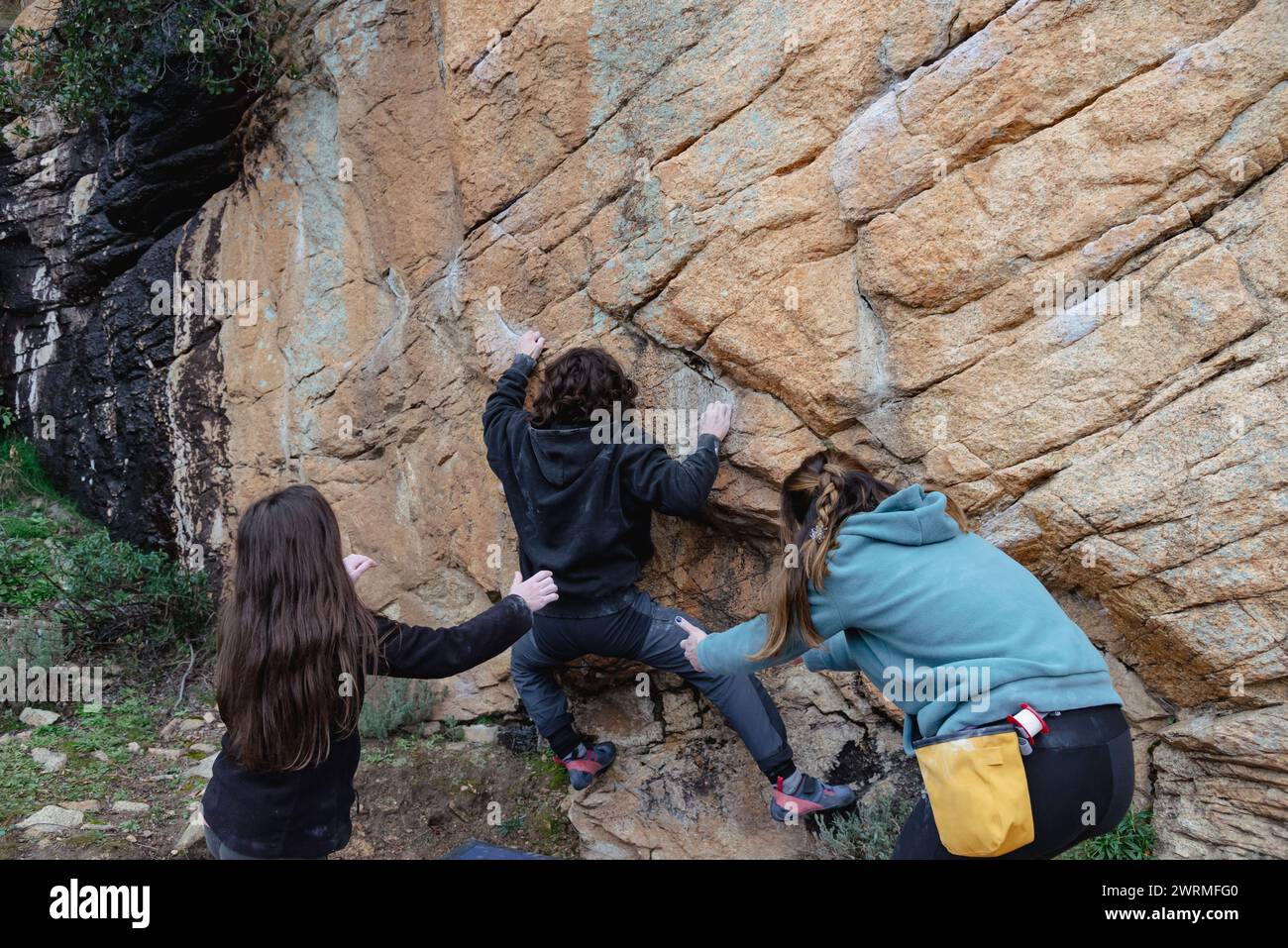 A climber is carefully ascending a steep rock face, guided and ...