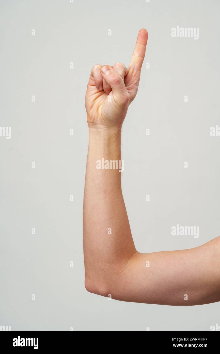 Male hand showing one finger up on gray background Stock Photo - Alamy