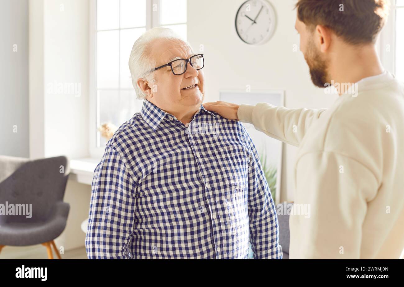 Senior old father and adult son bonding son places hand on father's ...