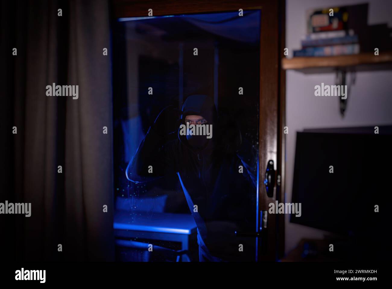 The thief looks through the glass inside the house Stock Photo - Alamy