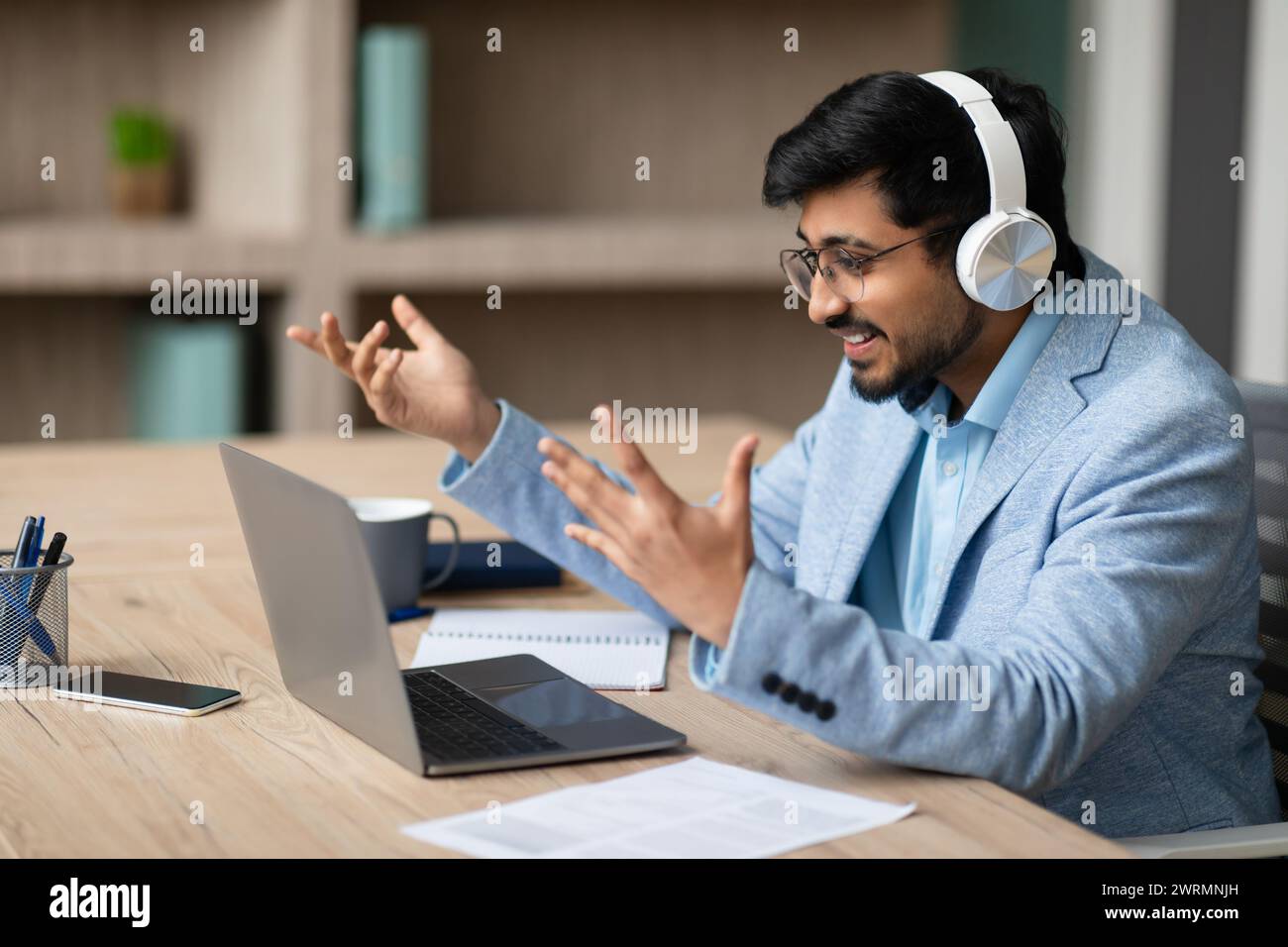 Hindu businessman wearing headphones communicating through video call ...
