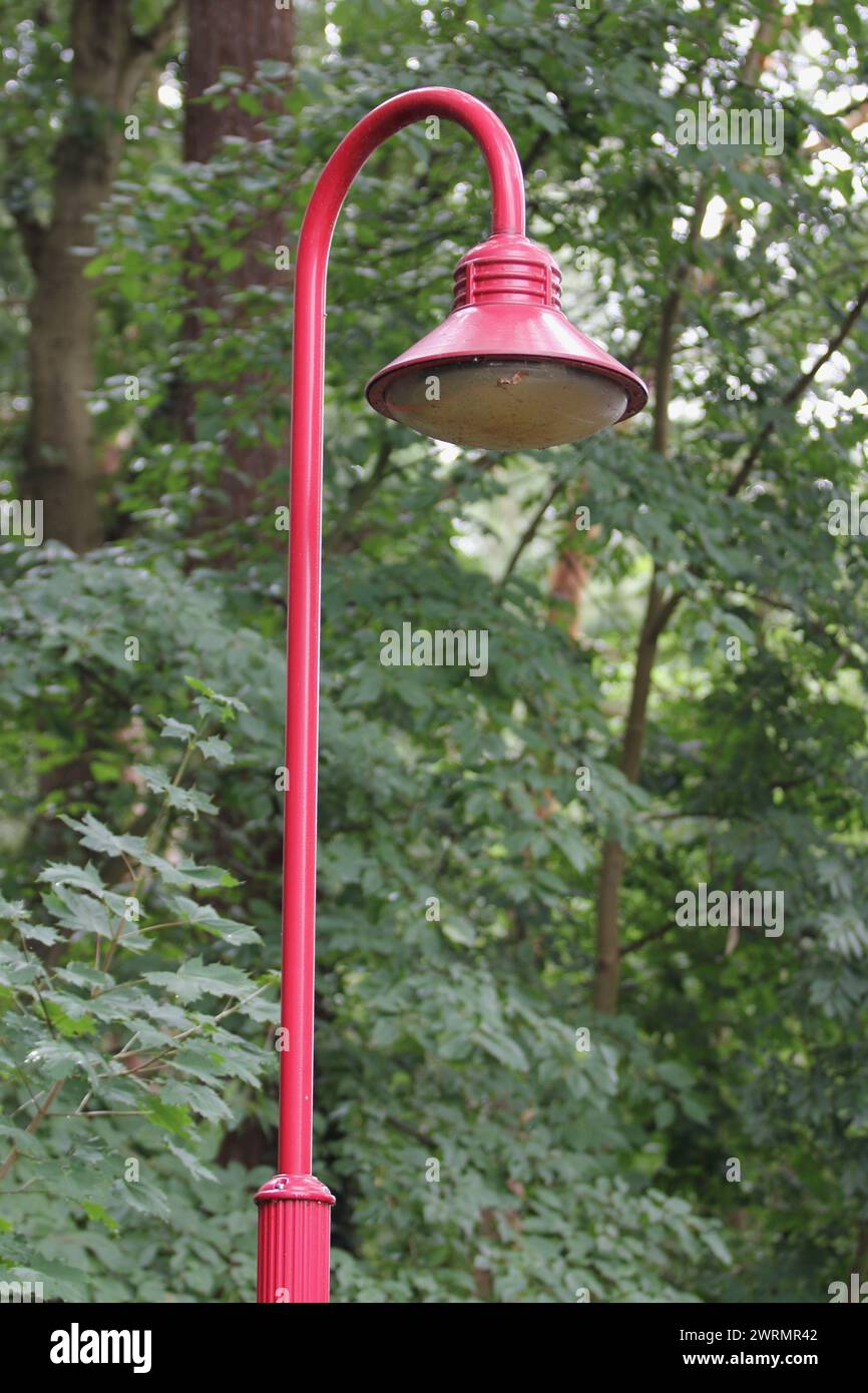 a red street lamp stands in front of a vegetated background Stock Photo ...