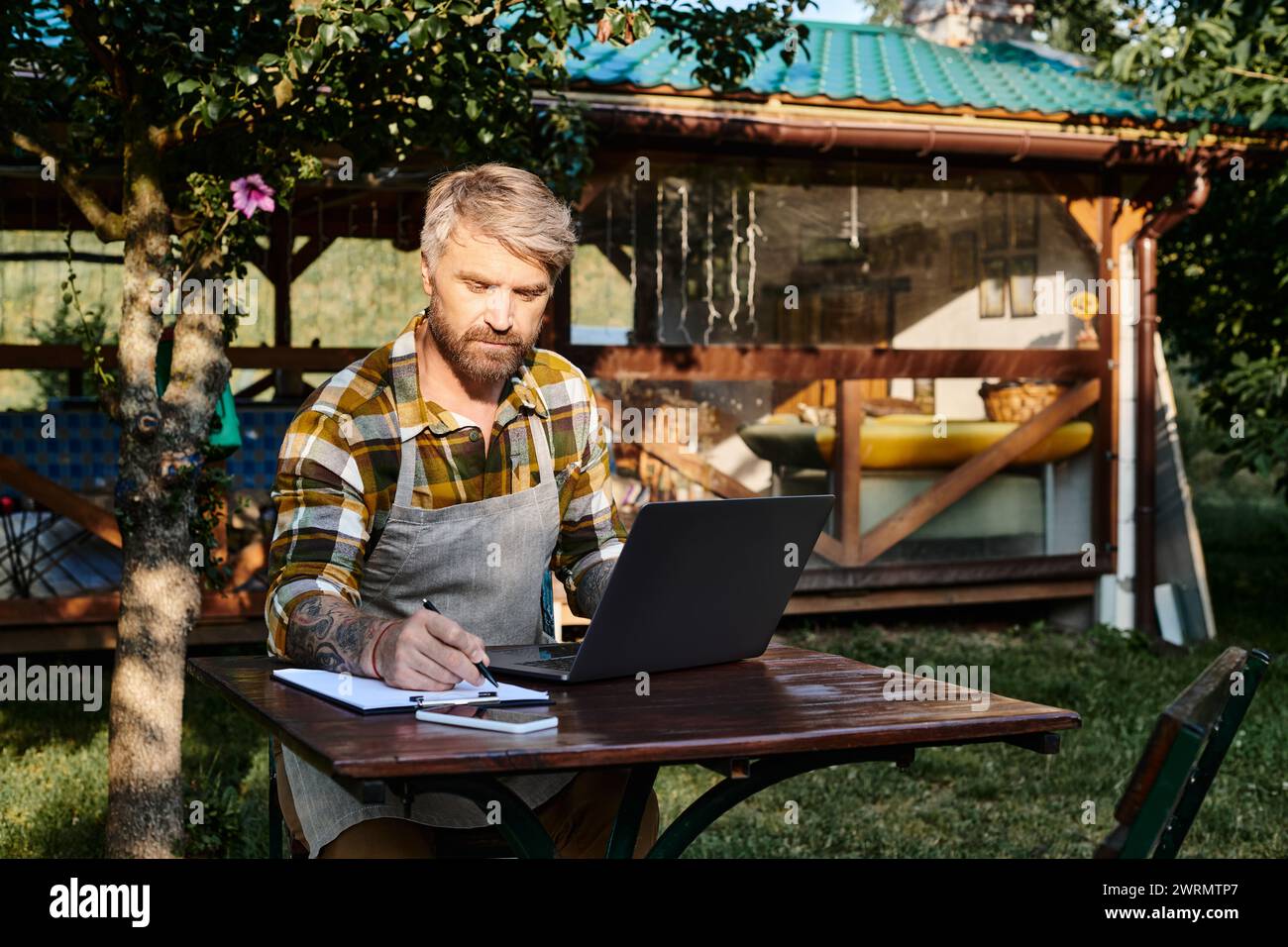 hard working handsome man with beard using laptop and clipboard to ...