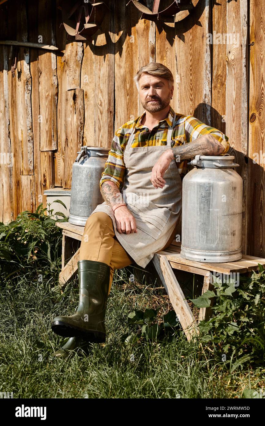 good looking farmer in casual attire with tattoos sitting with milk ...
