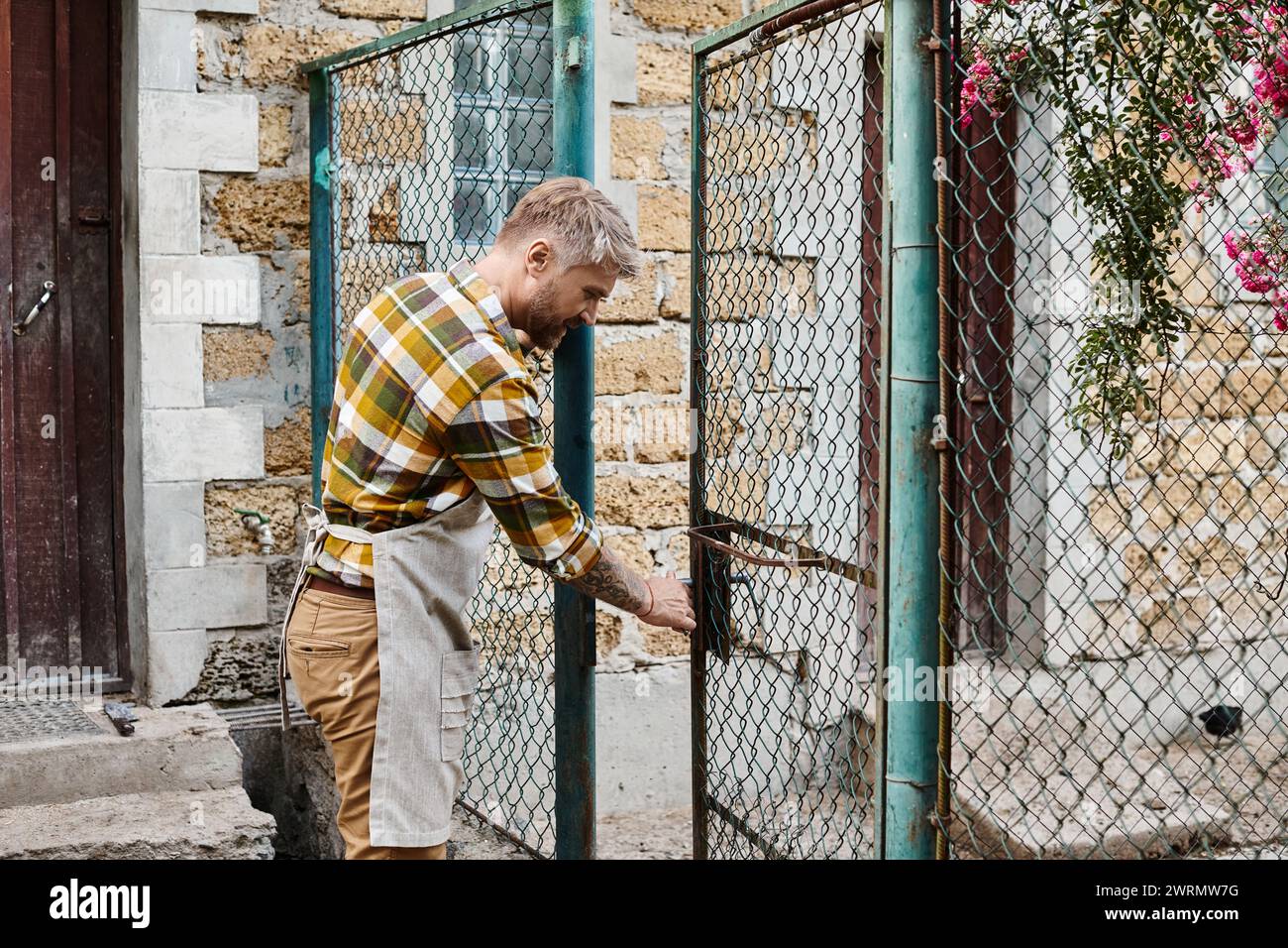 attractive bearded man in casual attire with tattoos opening enclosure ...