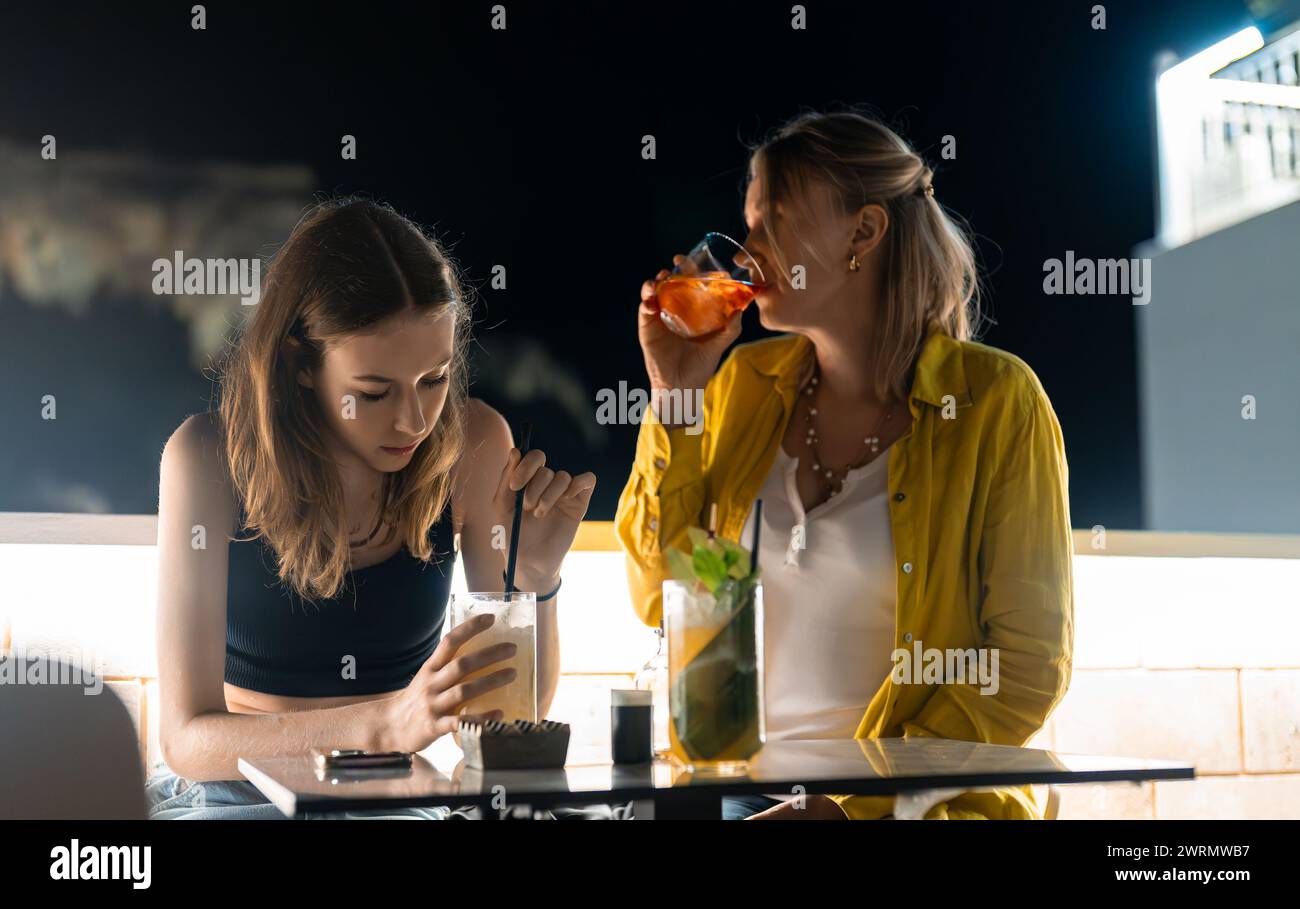 Two girls with cocktails at rooftop bar Stock Photo - Alamy