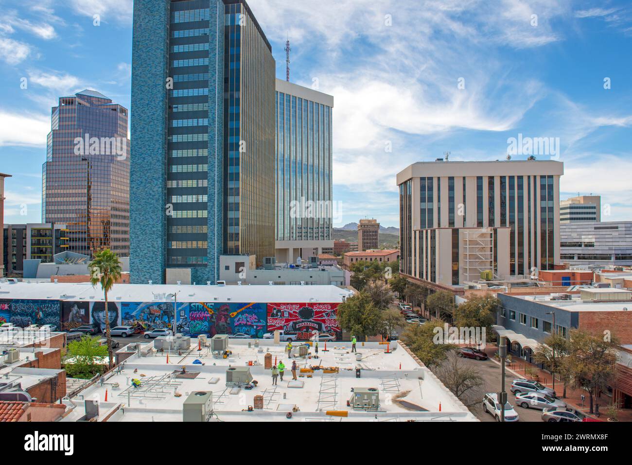 A-mid the skyscrapers, workers painting flat roofs with reflective ...