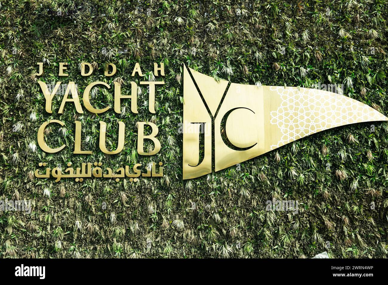 Golden emblem of jeddah yacht club over a textured grass surface ...