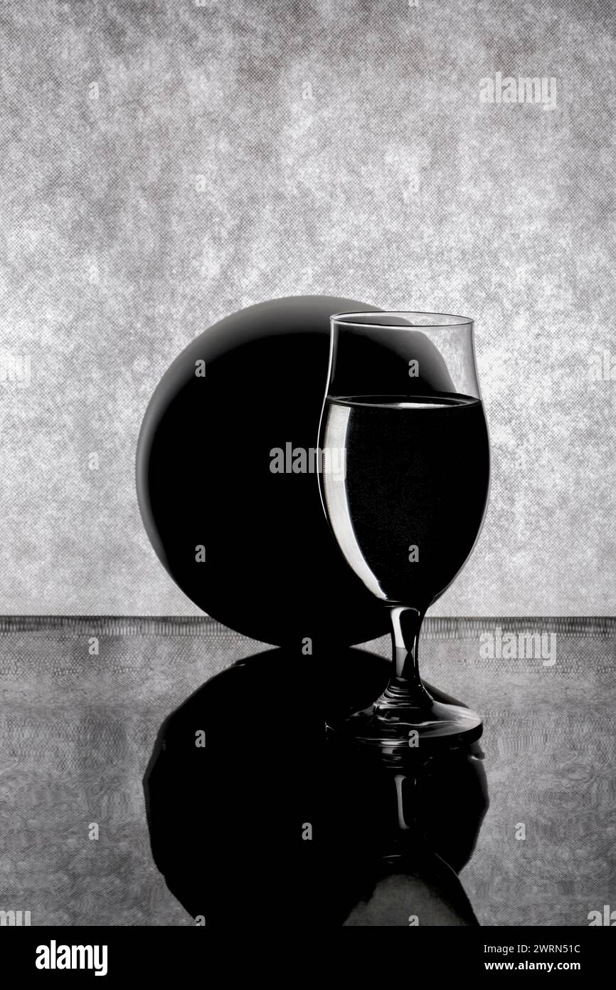 Still life with a glass of liquid and a large ball Stock Photo - Alamy