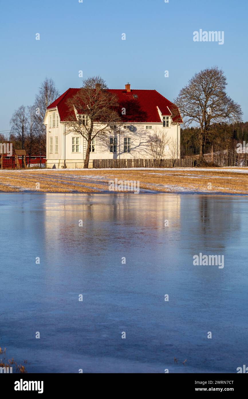 Old school building reflecting on a patch of melted ice Stock Photo - Alamy