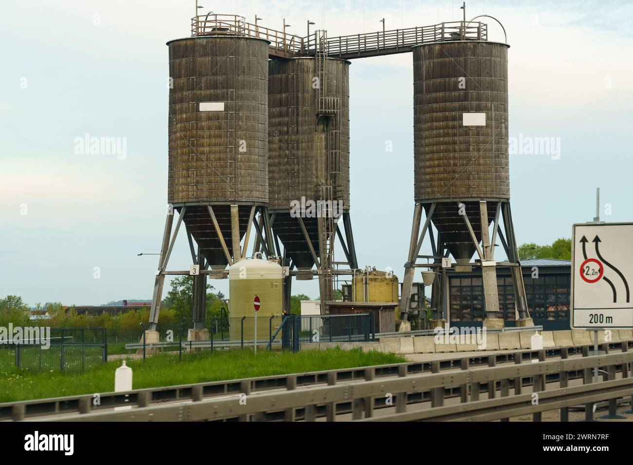 Two large silos standing next to a road, towering over the surrounding ...