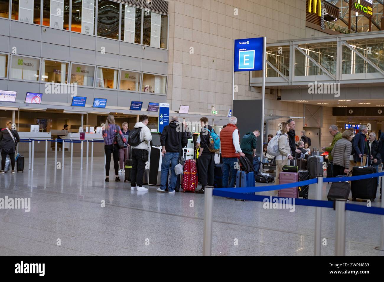 Airport terminal, passengers with luggage stand in line to check in for ...