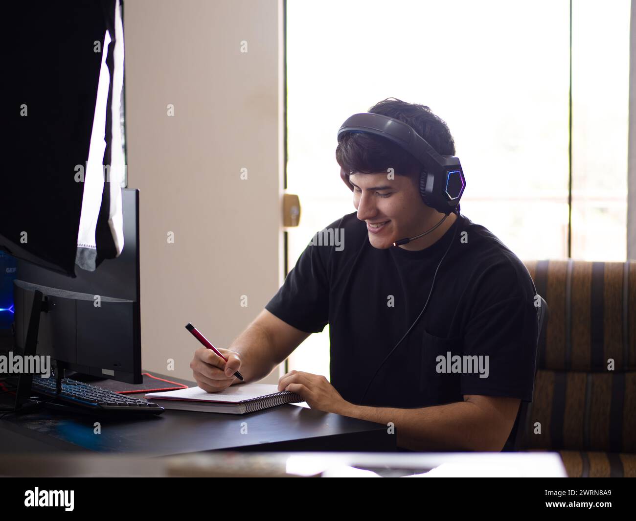 Image of a concentrated young man typing at his computer from his desk ...