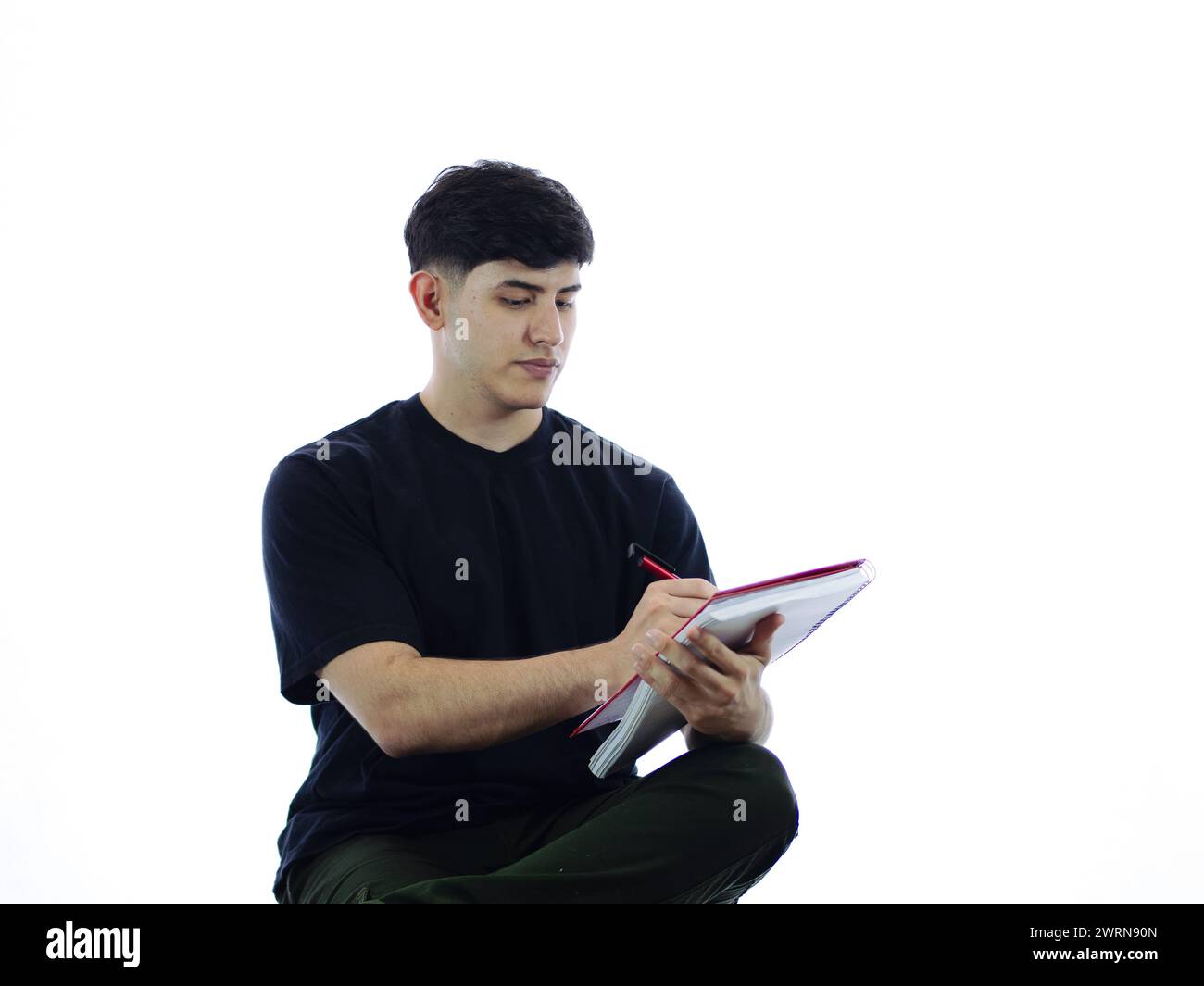 Image of a concentrated young man writing in a notebook, ideal for ...