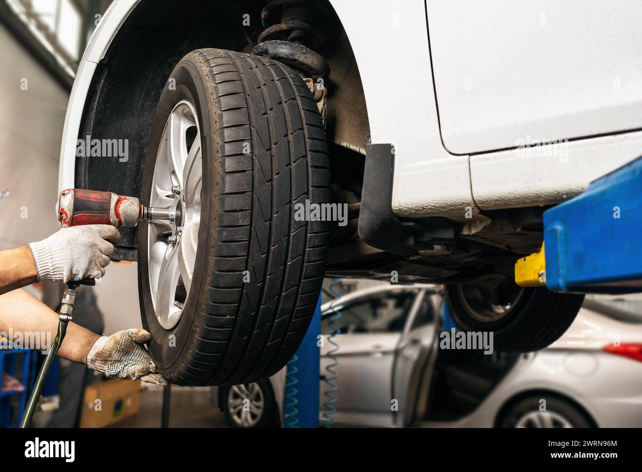 Auto mechanic tightens bolts on a wheel after repair using an air gun ...