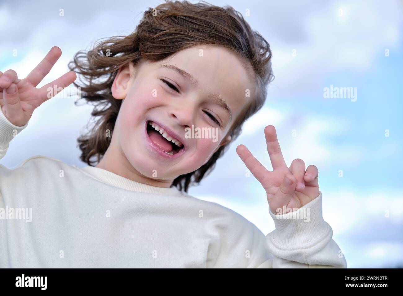 Cheerful cute girl showing two fingers gesture Stock Photo - Alamy