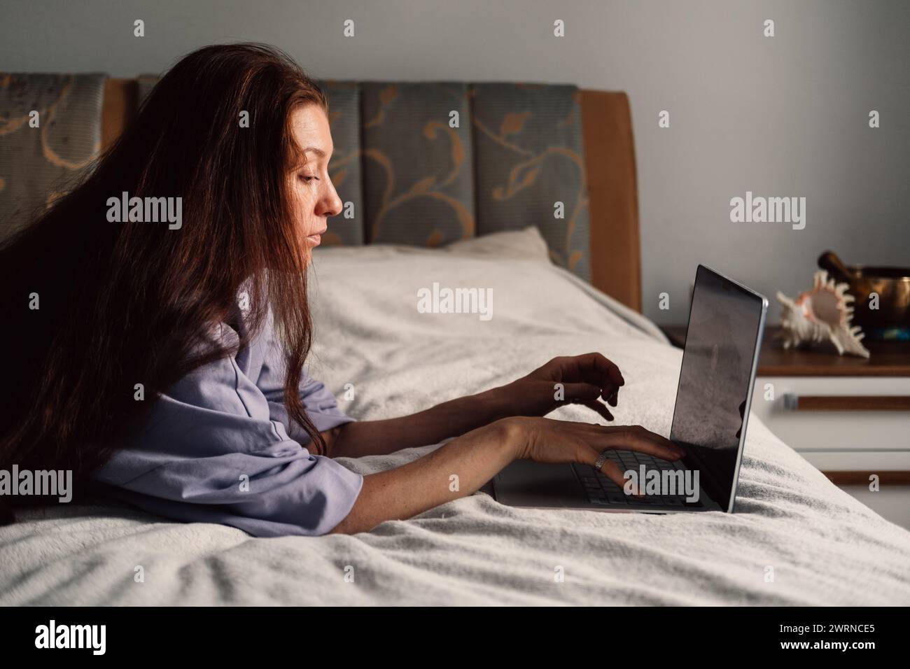Early rays of light peek through as a woman starts her day working from ...
