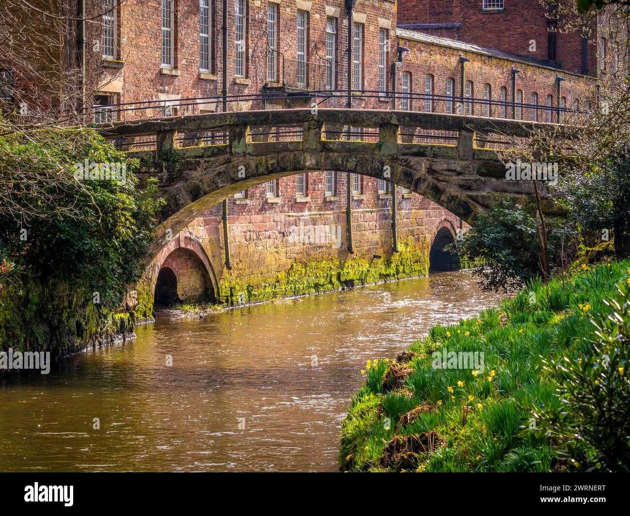 Packhorse Bridge crossing the river Bollin with Quarry Bank Mill behind ...