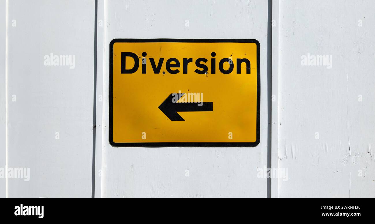 Yellow diversion sign with black left facing arrow Stock Photo - Alamy