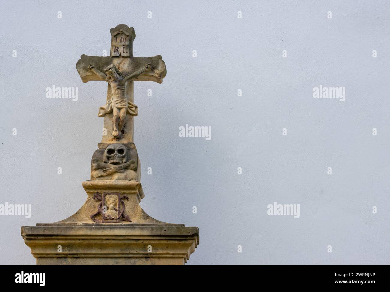 Historical cross of a tomb, with Jesus Christ and a skull. White wall ...