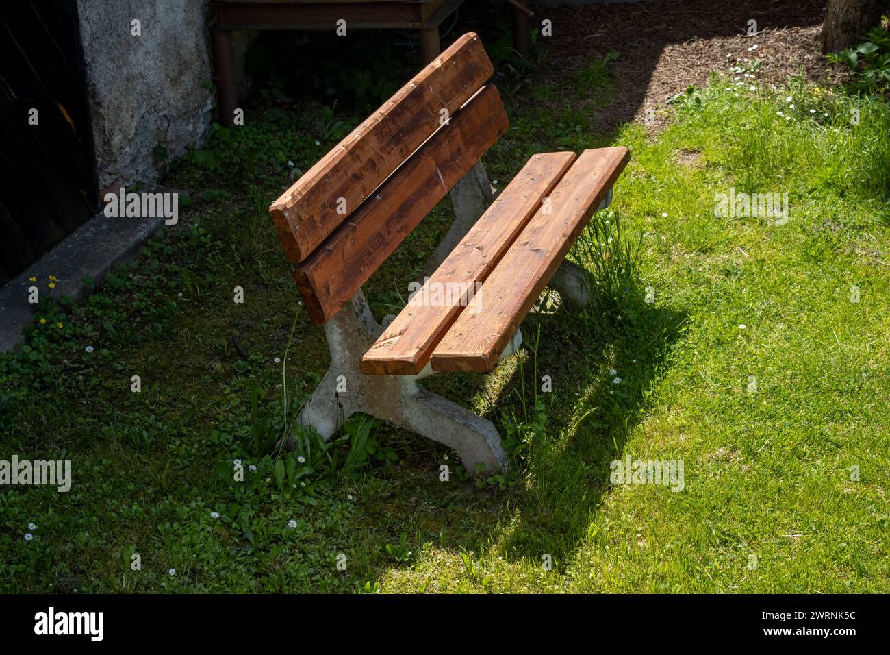 Wooden bench on a bright green spring grass. Sunny day. Located in a ...