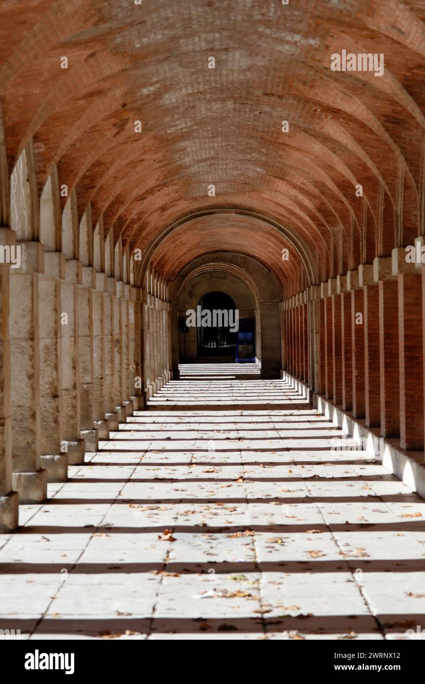Long walkway in an aged brick building with a clock Stock Photo - Alamy