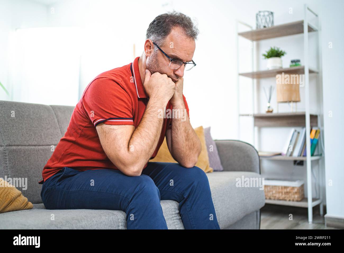 Man sitting alone at home looking sad and distraught Stock Photo - Alamy